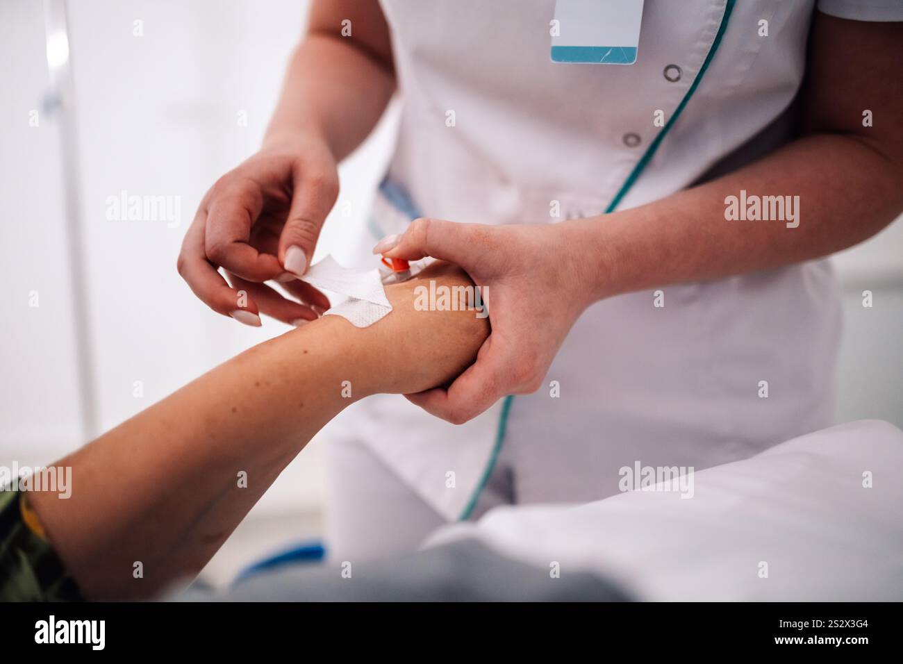 A nurse places an adhesive bandage on a patient's arm following an ...