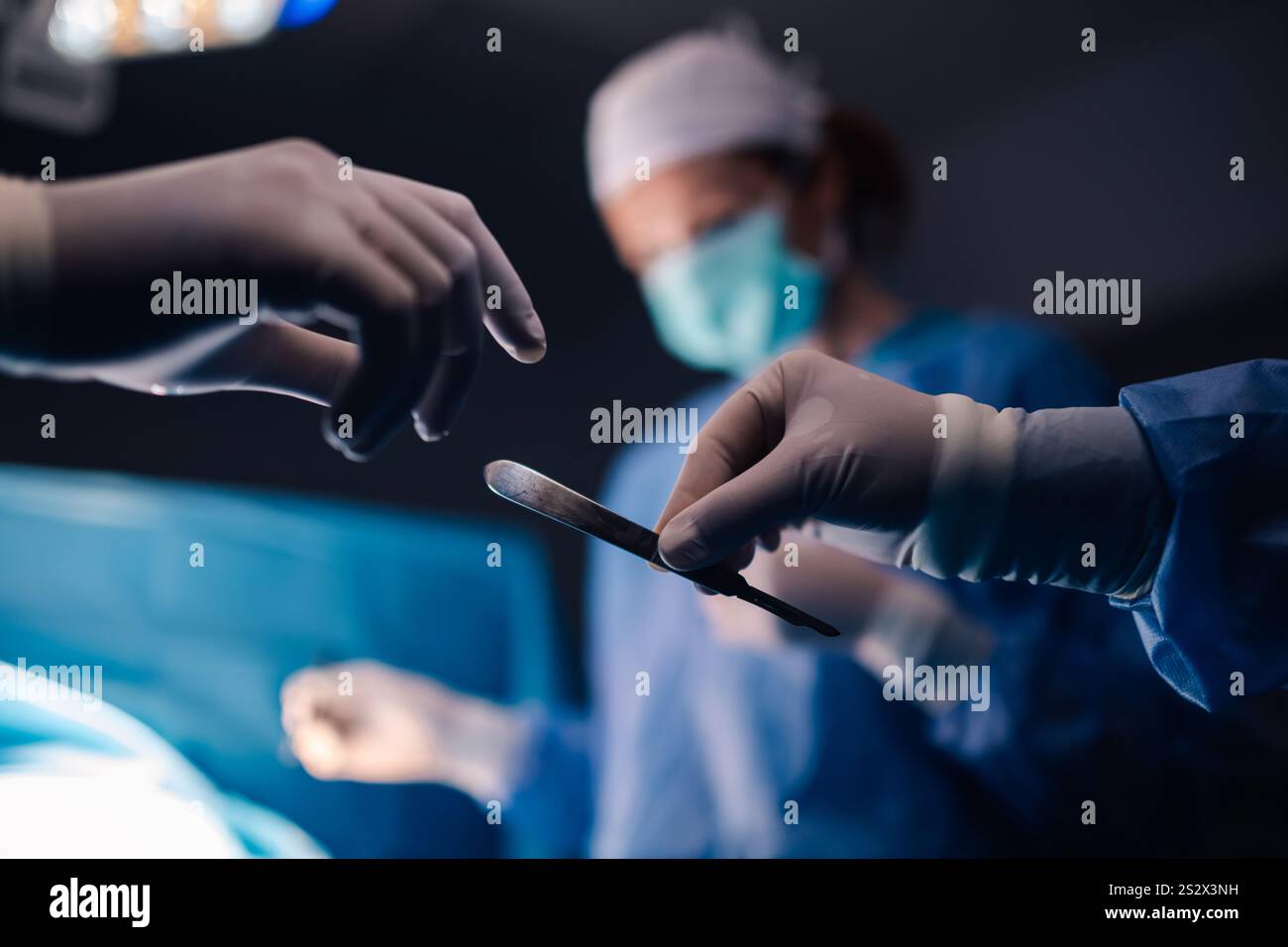 A surgeon is seen passing a scalpel to an assistant in the operating ...