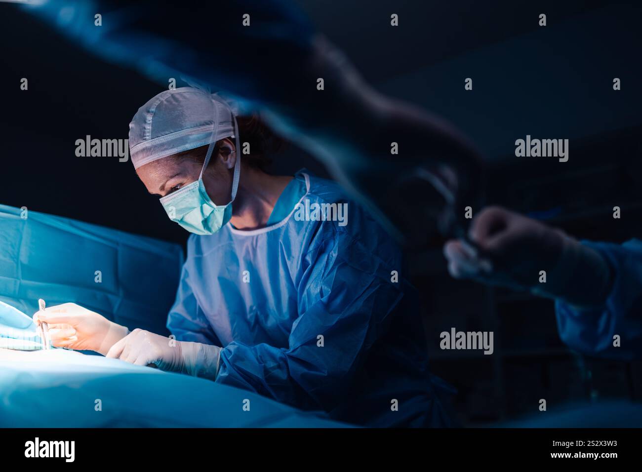 A female surgeon in full surgical attire is seen concentrating on an ...