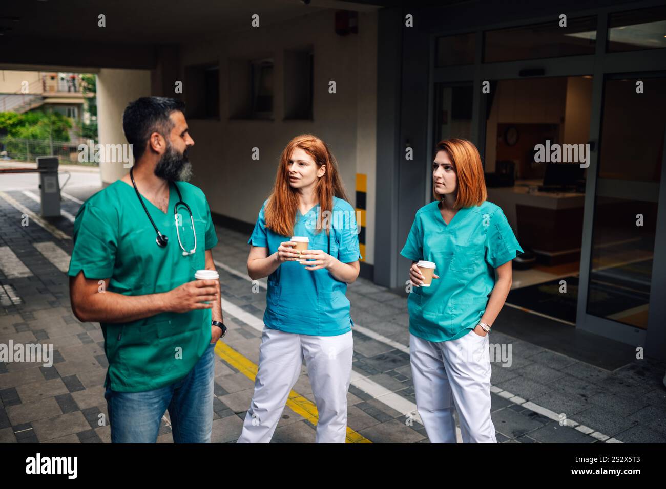 A group of doctors and nurses in green scrubs taking a coffee break ...