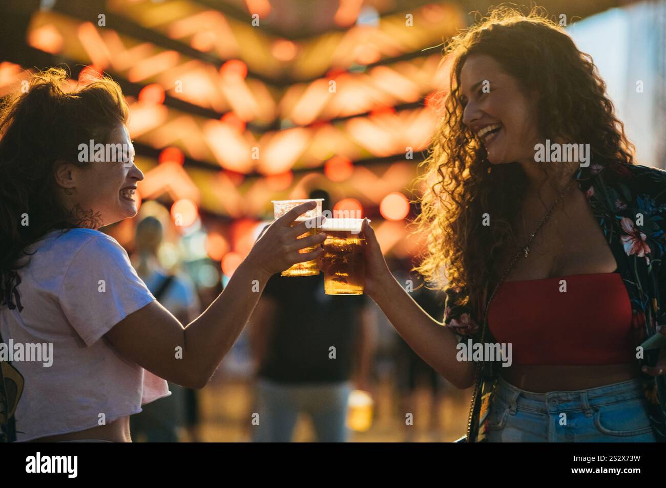 Two beautiful friends drinking beer and having fun on a music festival ...