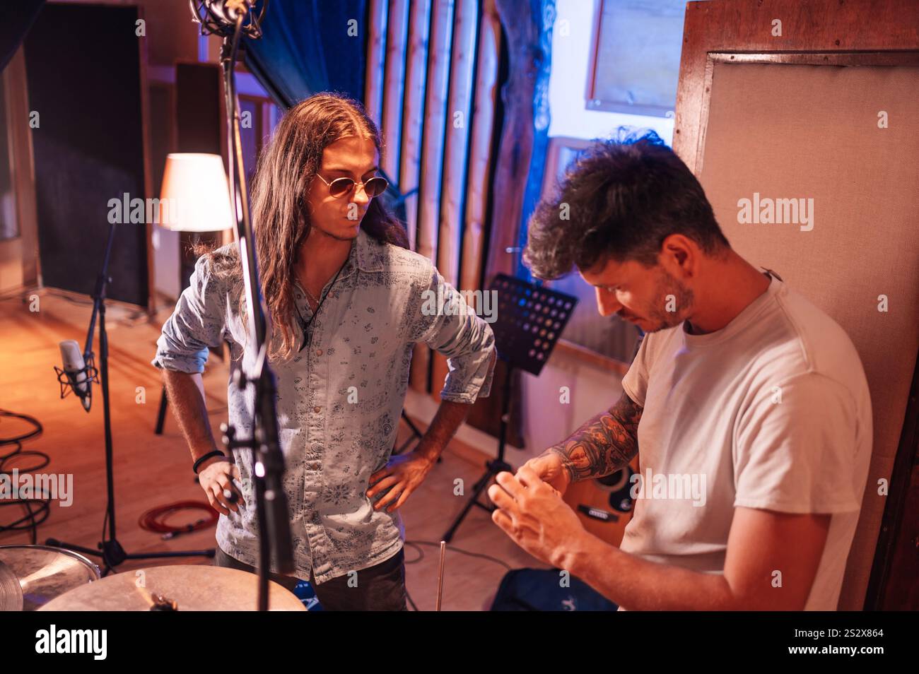 Portrait of a two male musicians assembling drums in a soundproof booth ...