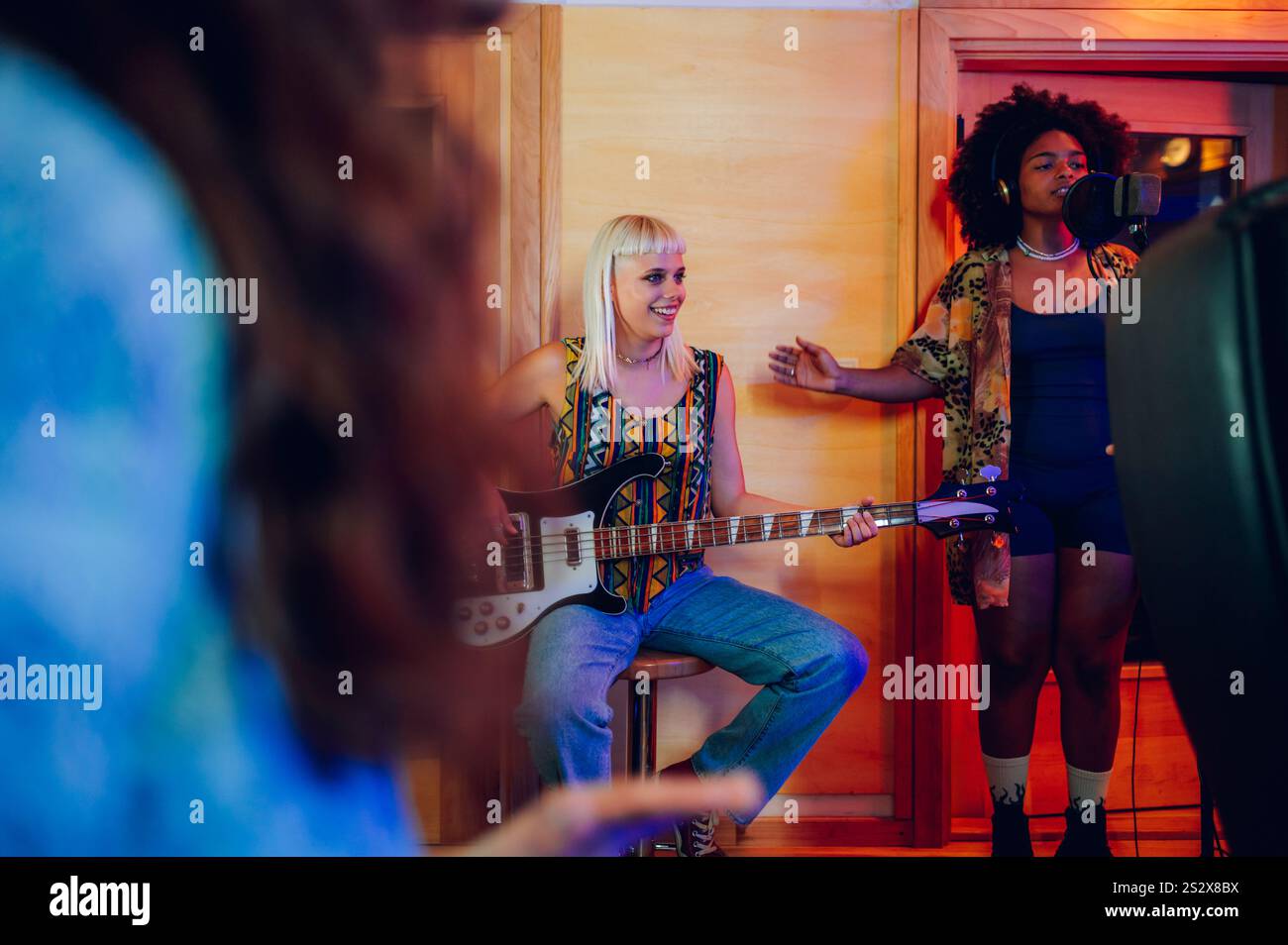 Smiling multicultural female band standing at music recording studio ...