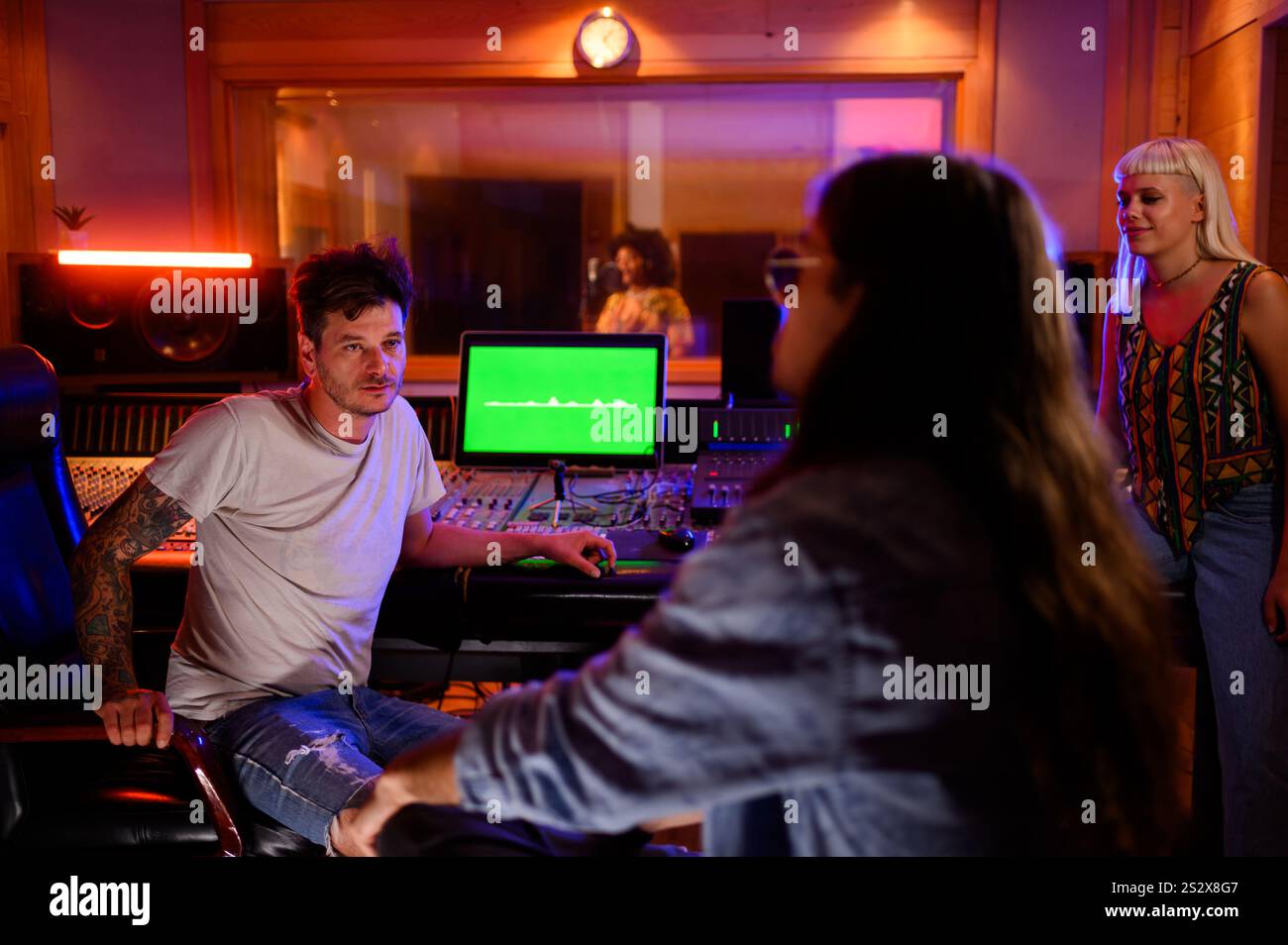 Three young talented band members are talking in a studio while their ...