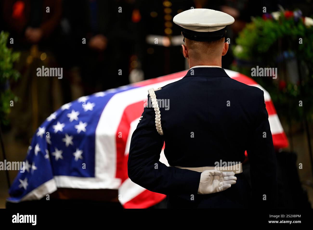 A member of the Military Honor Guard stands before the flag draped ...