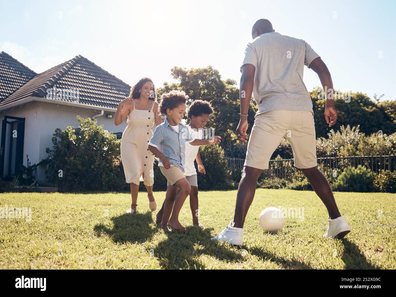 Happy, football and parents playing with children in backyard for ...
