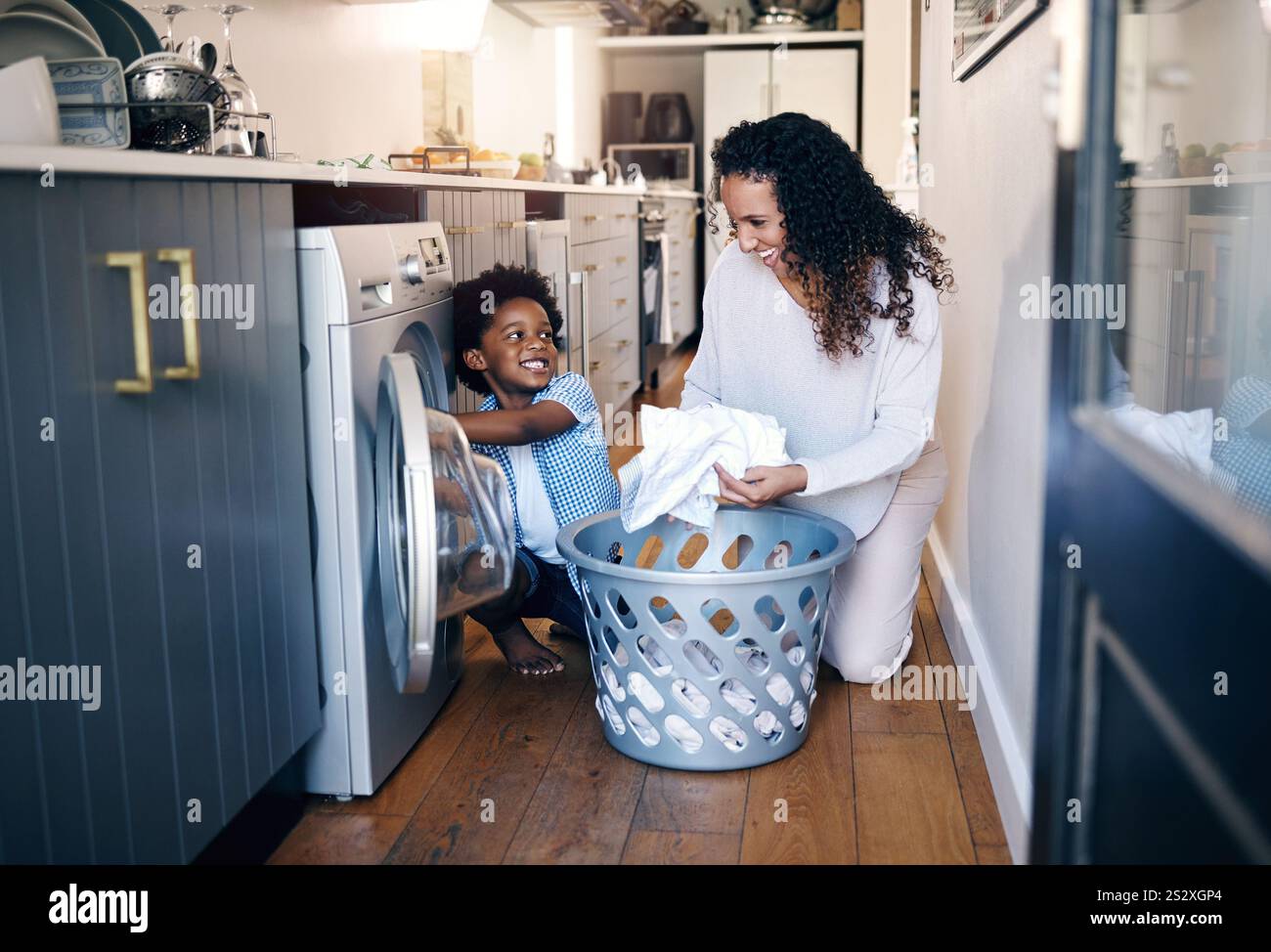 Home, mom and child with machine for laundry, household chores and kid ...