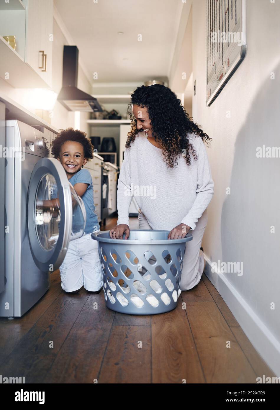Home, mother and child with machine for laundry, household chores and ...