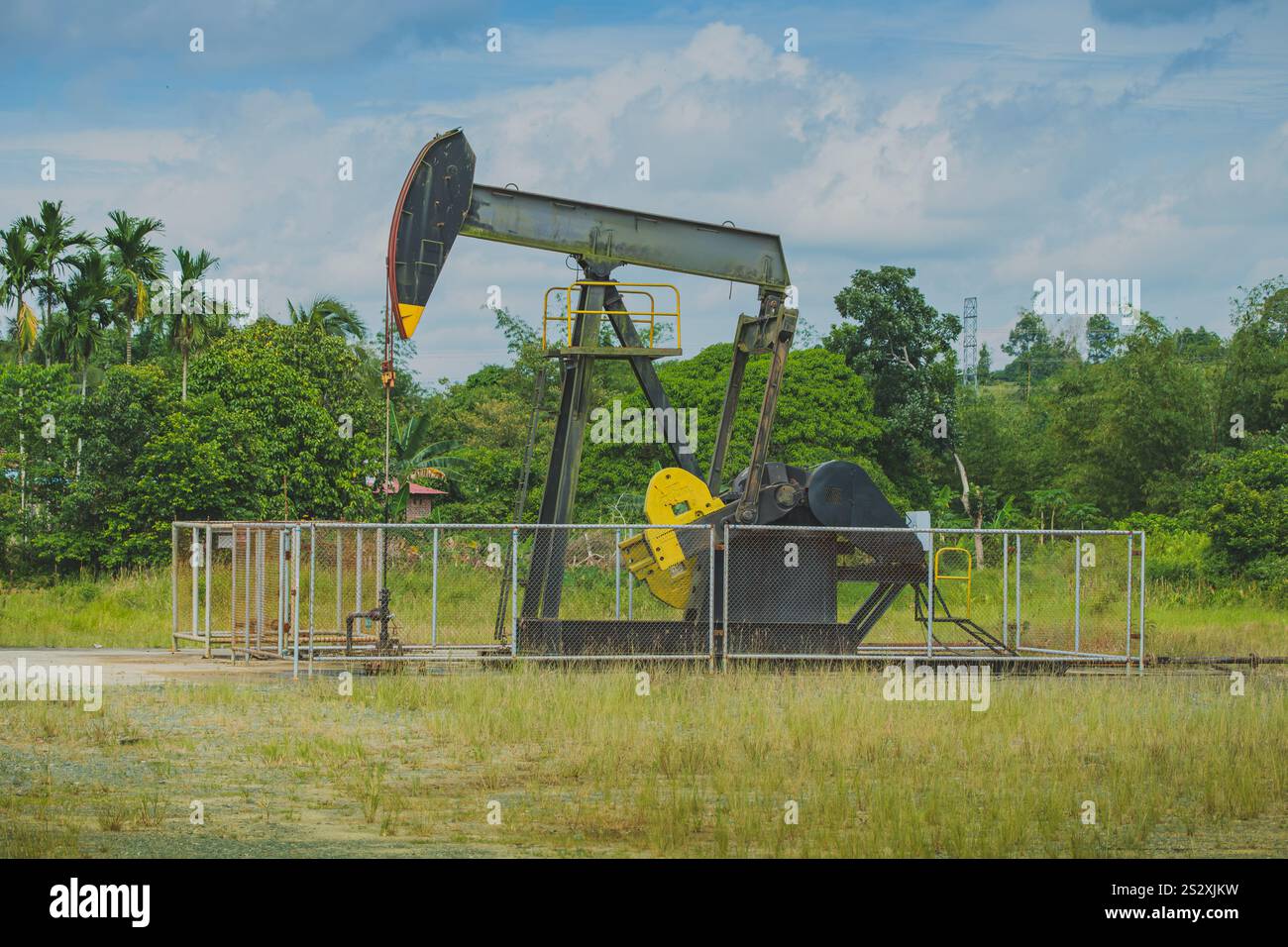 A photo of an oil well pump jack operating in a tropical environment ...