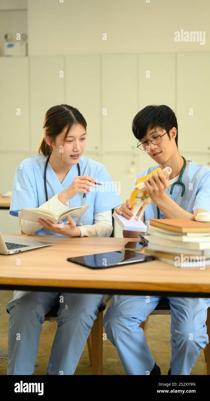 Medical students in blue scrubs studying an anatomical mode in modern ...