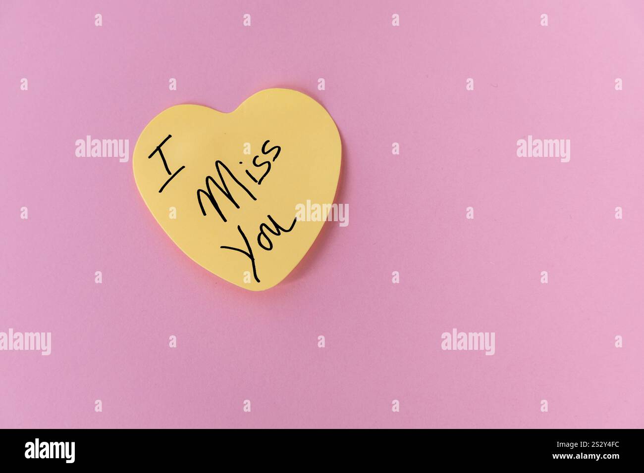 A yellow, heart-shaped Post-It note featuring the handwritten message ...