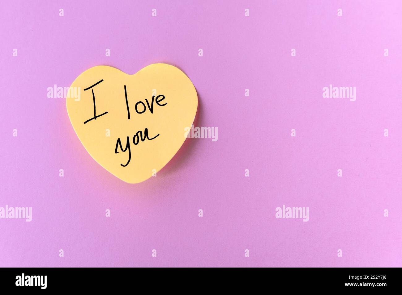A yellow, heart-shaped Post-It note featuring the handwritten message ...