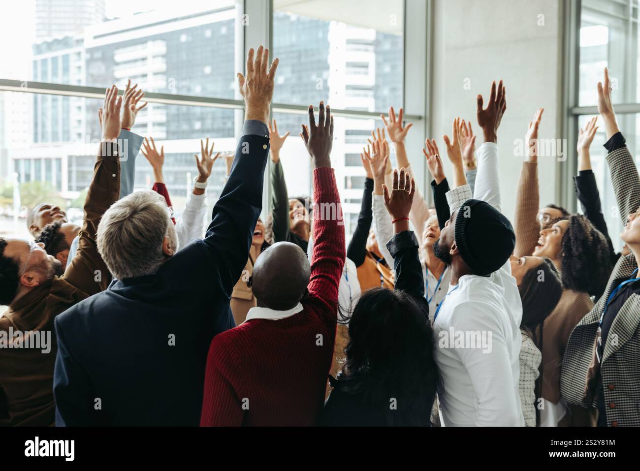 Diverse corporate team celebrates unity and success by raising hands ...