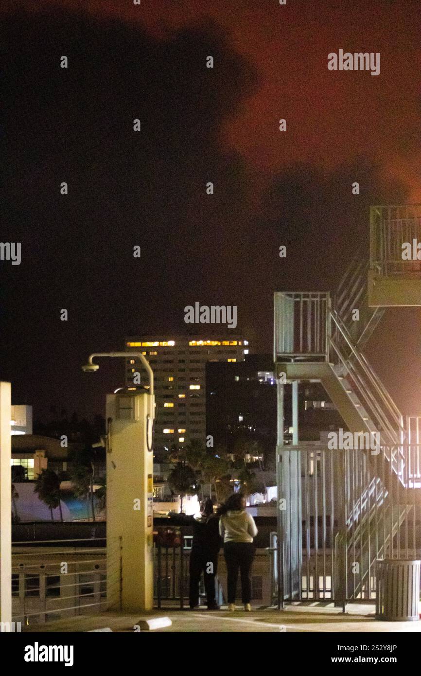 Los Angeles, USA. 7th January, 2025. Two women watch as plumes of fiery ...