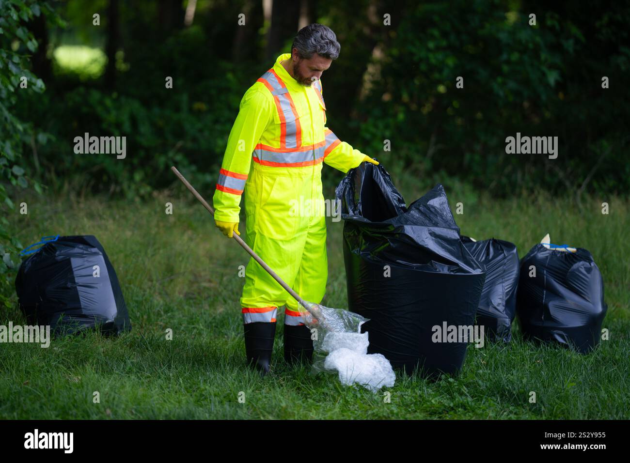 Volunteer man collecting garbage, picking up waste at nature. Land ...