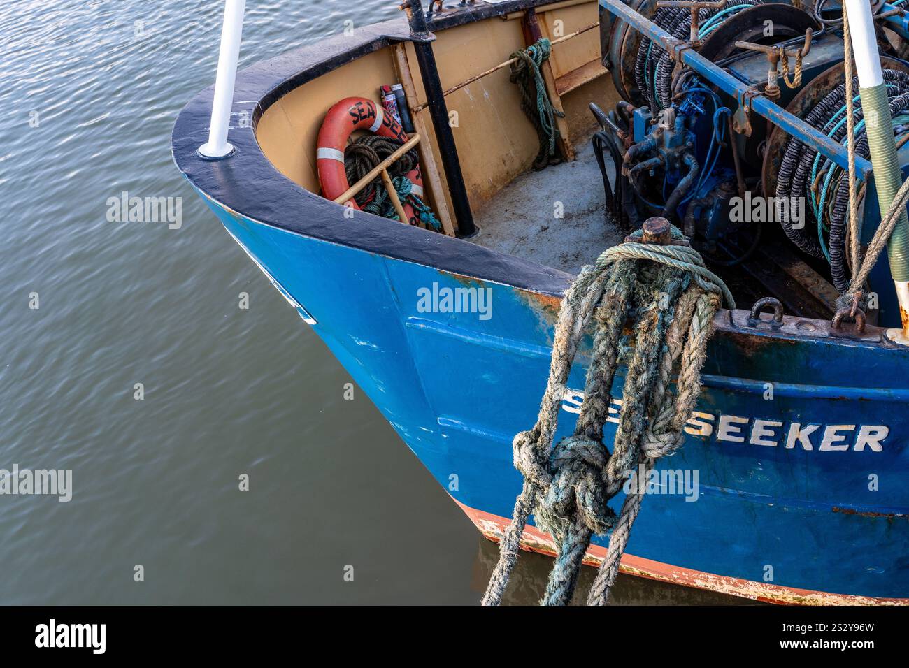Fishing trawler prow tied up by nylon rope to the quayside at West Bay ...