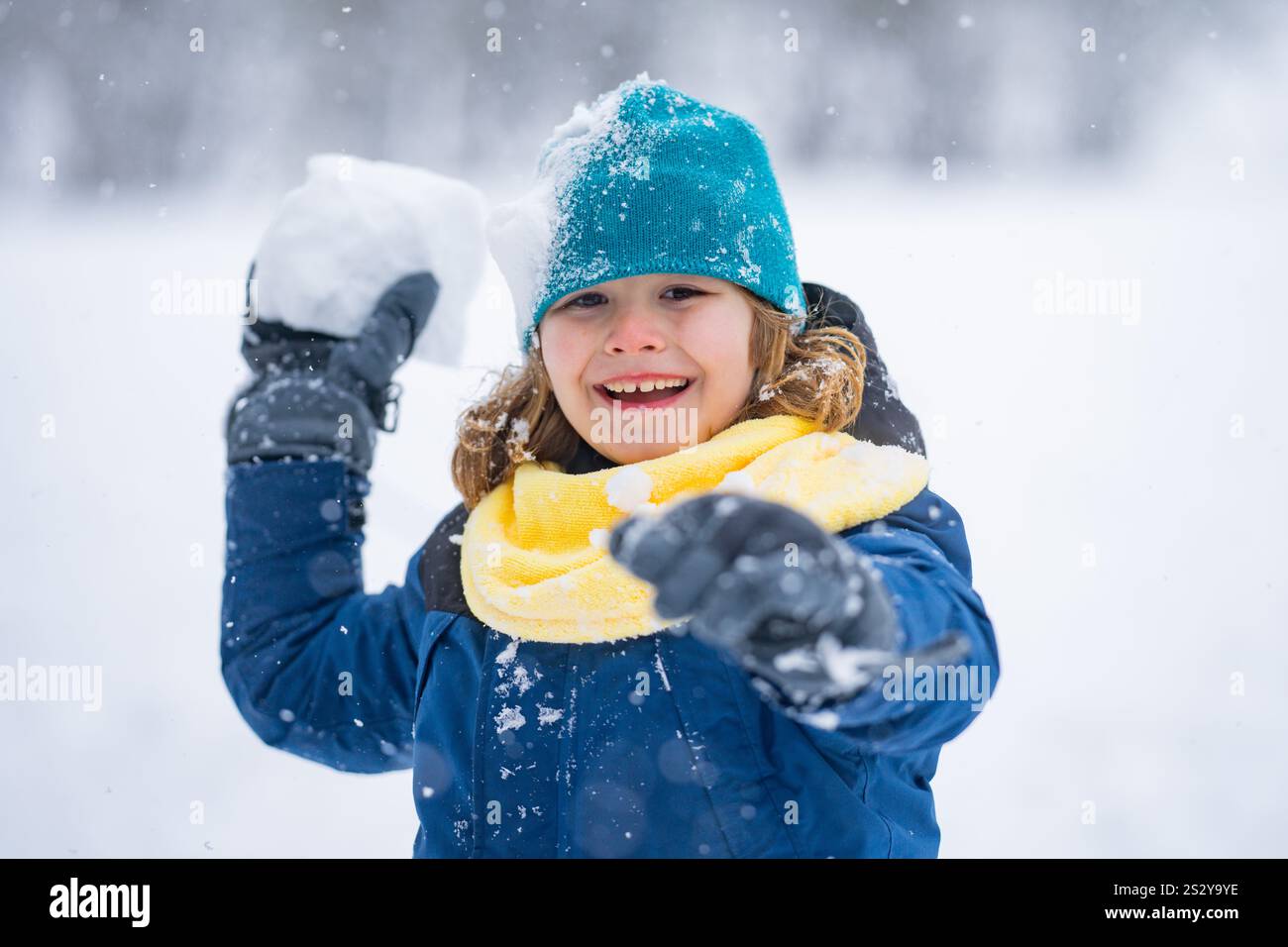 Happy Child playing with snow, outdoors during snowfall. Winter child ...