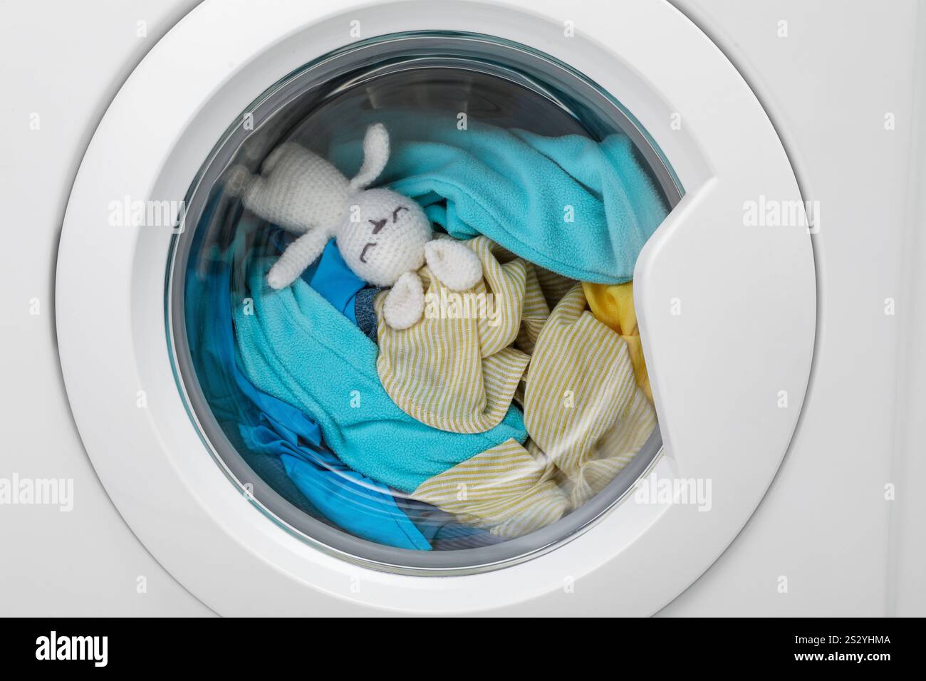 Washing machine with clothes and toy bunny as background, closeup Stock ...