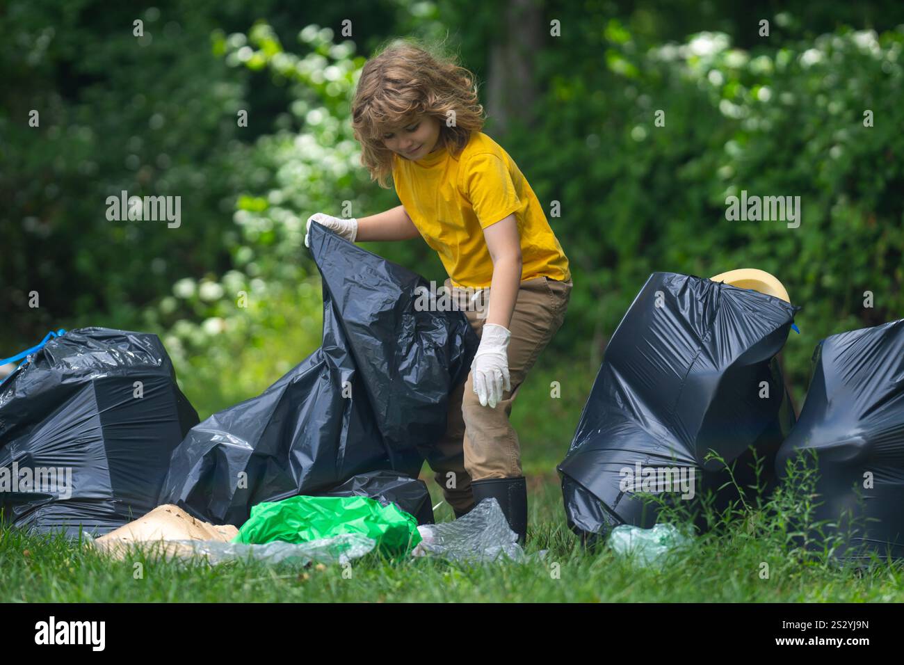 Child boy picking up plastic bottle outdoor. Save environmental and ...