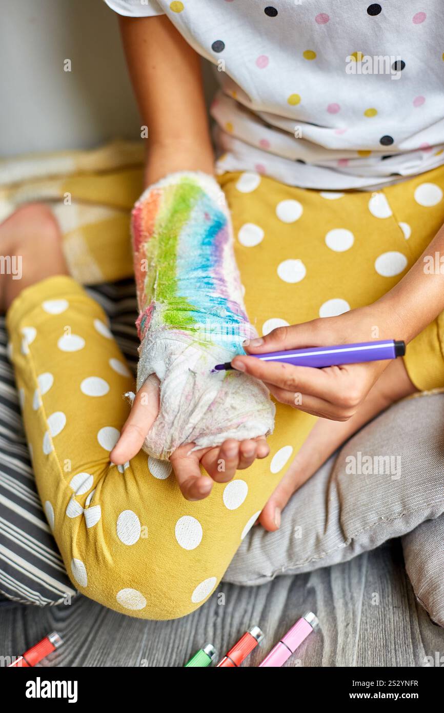 Teen girl with a broken arm at home draws an orthopedic cast, casted ...