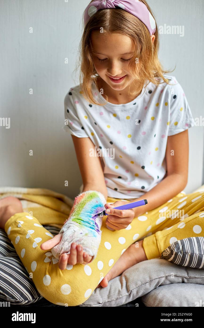 Teen girl with a broken arm at home draws an orthopedic cast, casted ...
