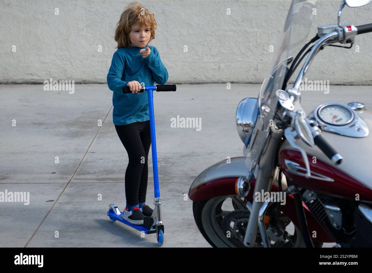 Kid future. The surprised child saw a big motorcycle outdoor. He dreams ...