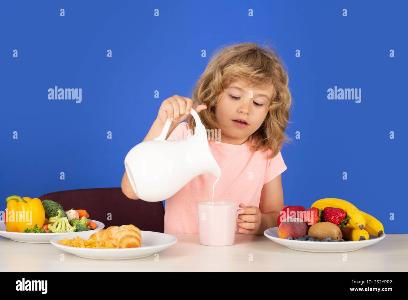 Cute kid drinking milk on blue studio background. Kid with dairy milk ...