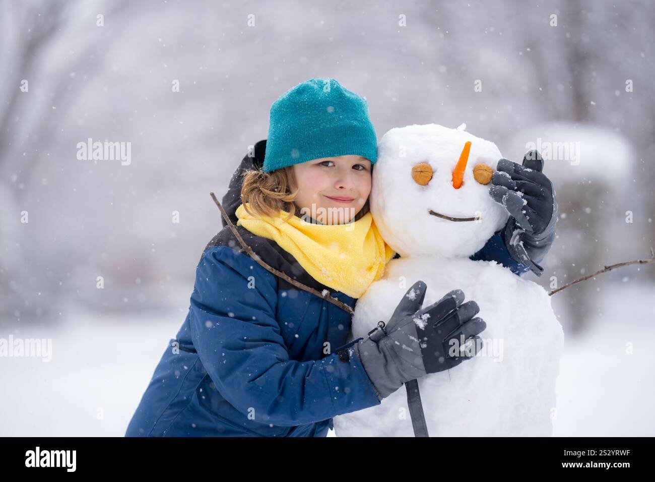 Winter child play with snowman in winter. Snowman with a carrot nose on ...
