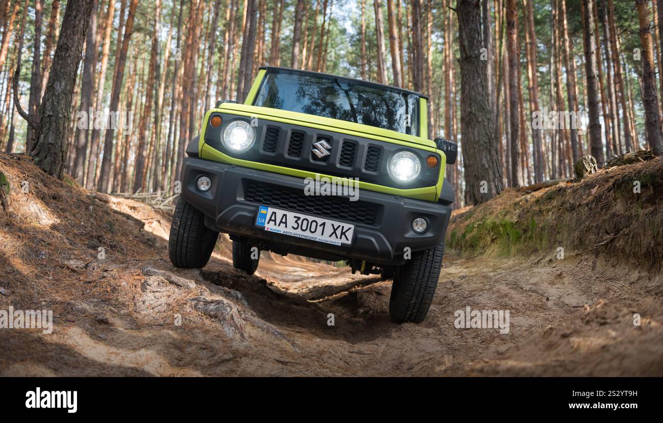 Lime green Suzuki Jimny in pine forest. Front view of off-road mini SUV ...