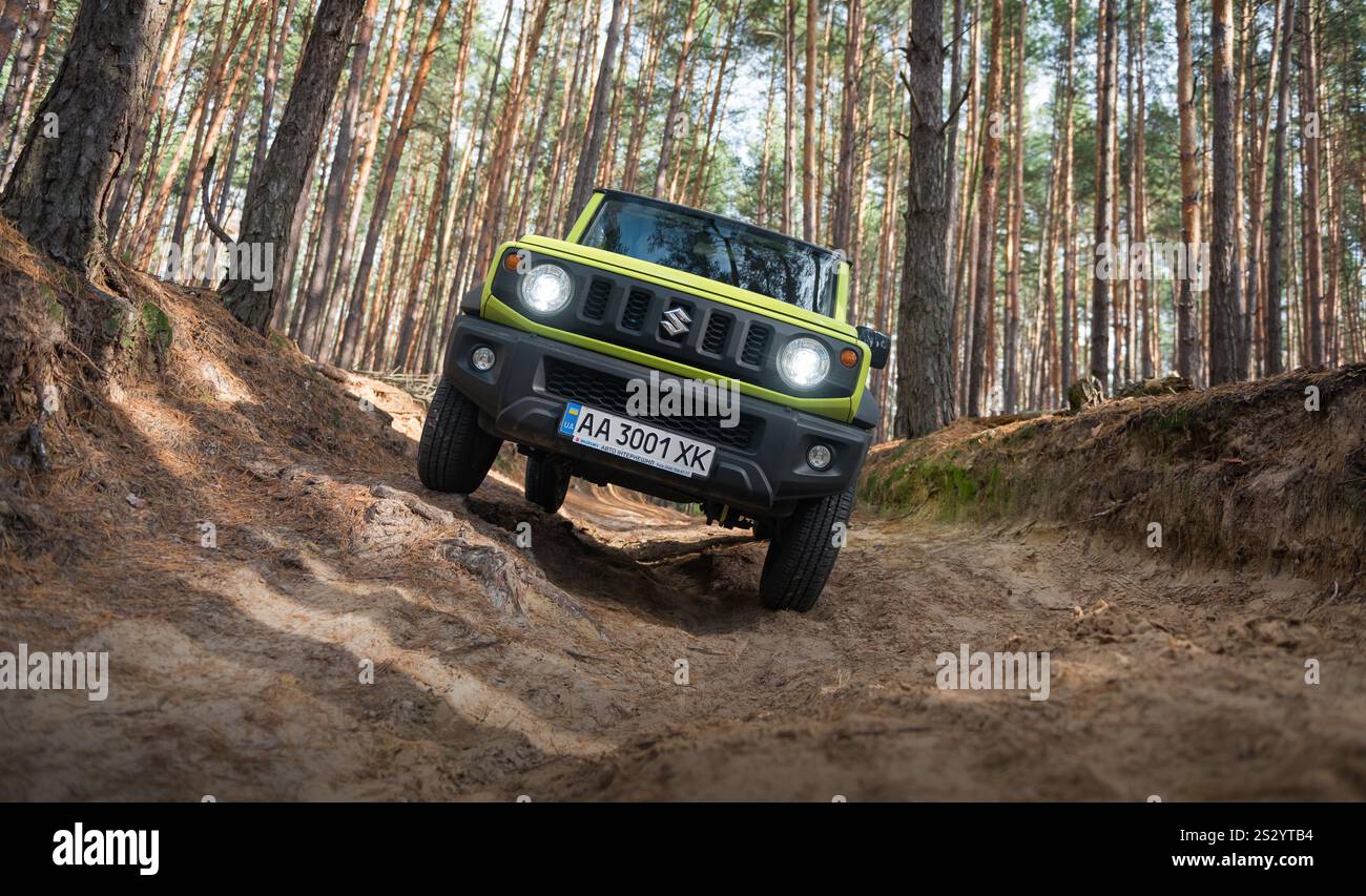 Lime green Suzuki Jimny in pine forest. Front view of off-road mini SUV ...