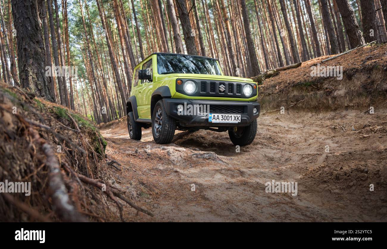 Lime green Suzuki Jimny in pine forest. Three quarter front view of off ...