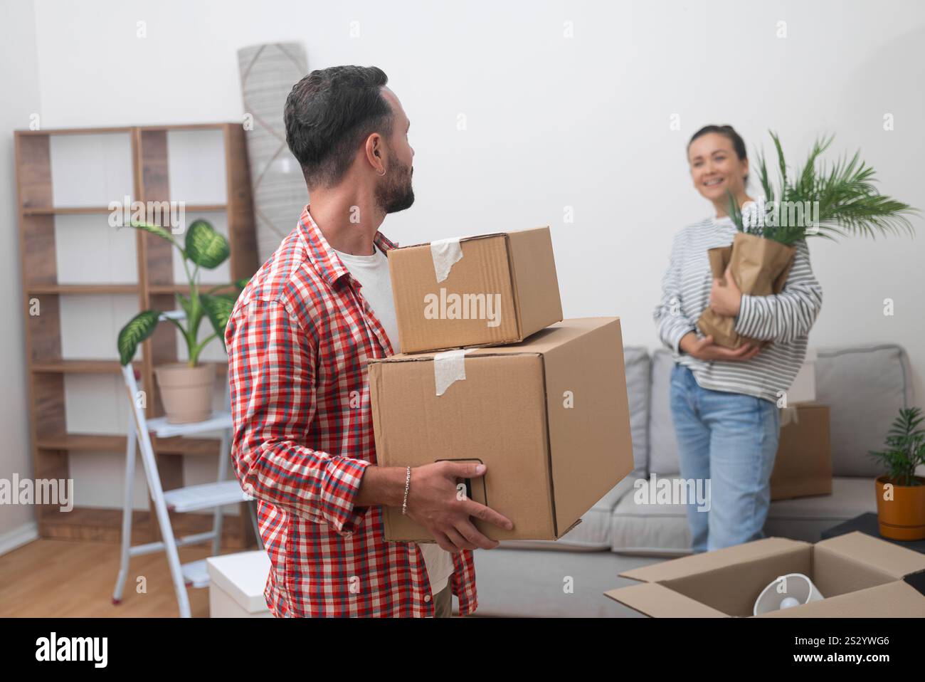 Young friends enters their new home living room with heap of cardboard ...
