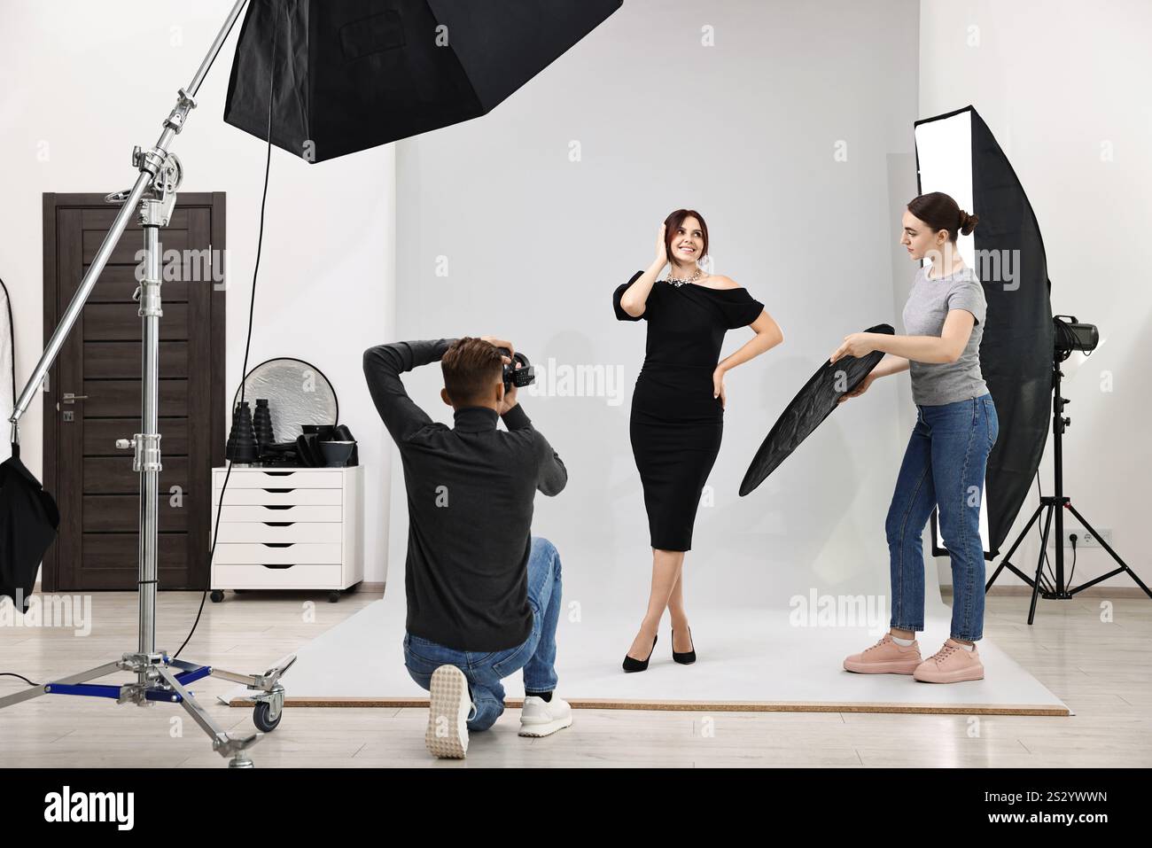 Photographer and assistant working with model in professional photo ...