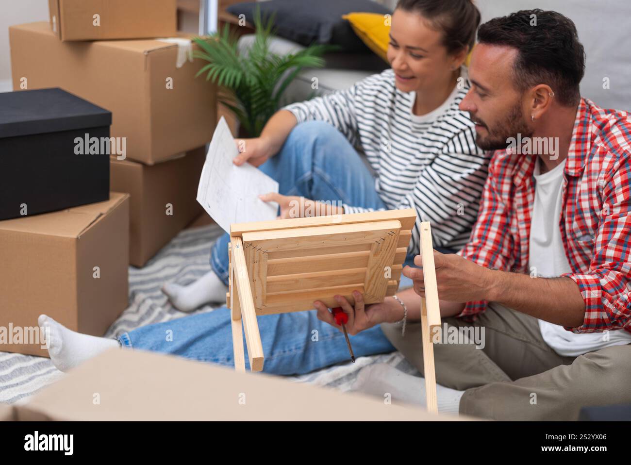 couple assembles a DIY shelf amidst moving carton boxes, adding a ...