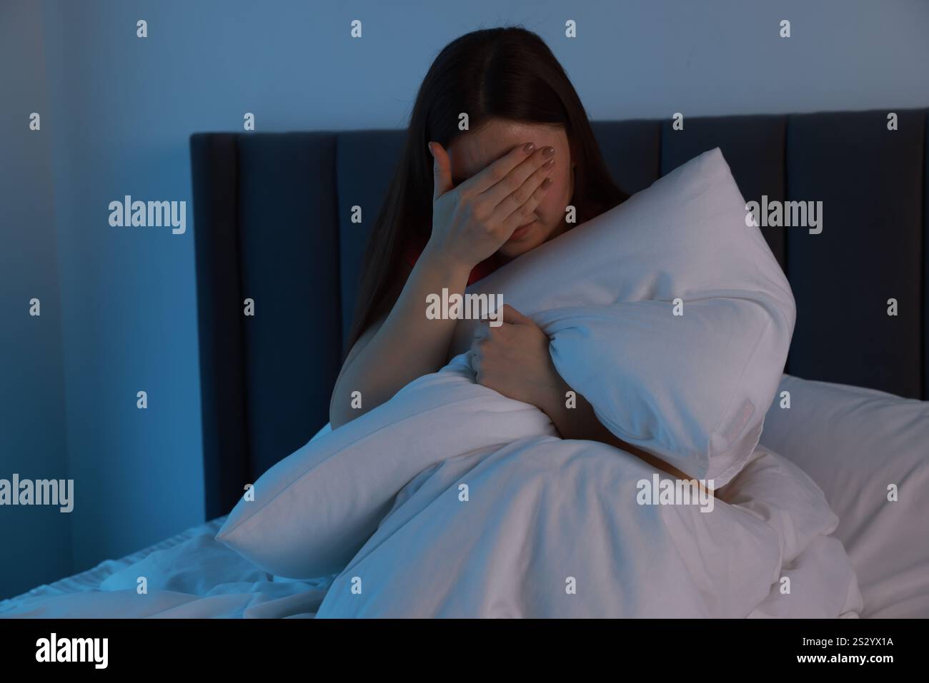 Fear of darkness. Scared young woman on bed in room at night Stock ...