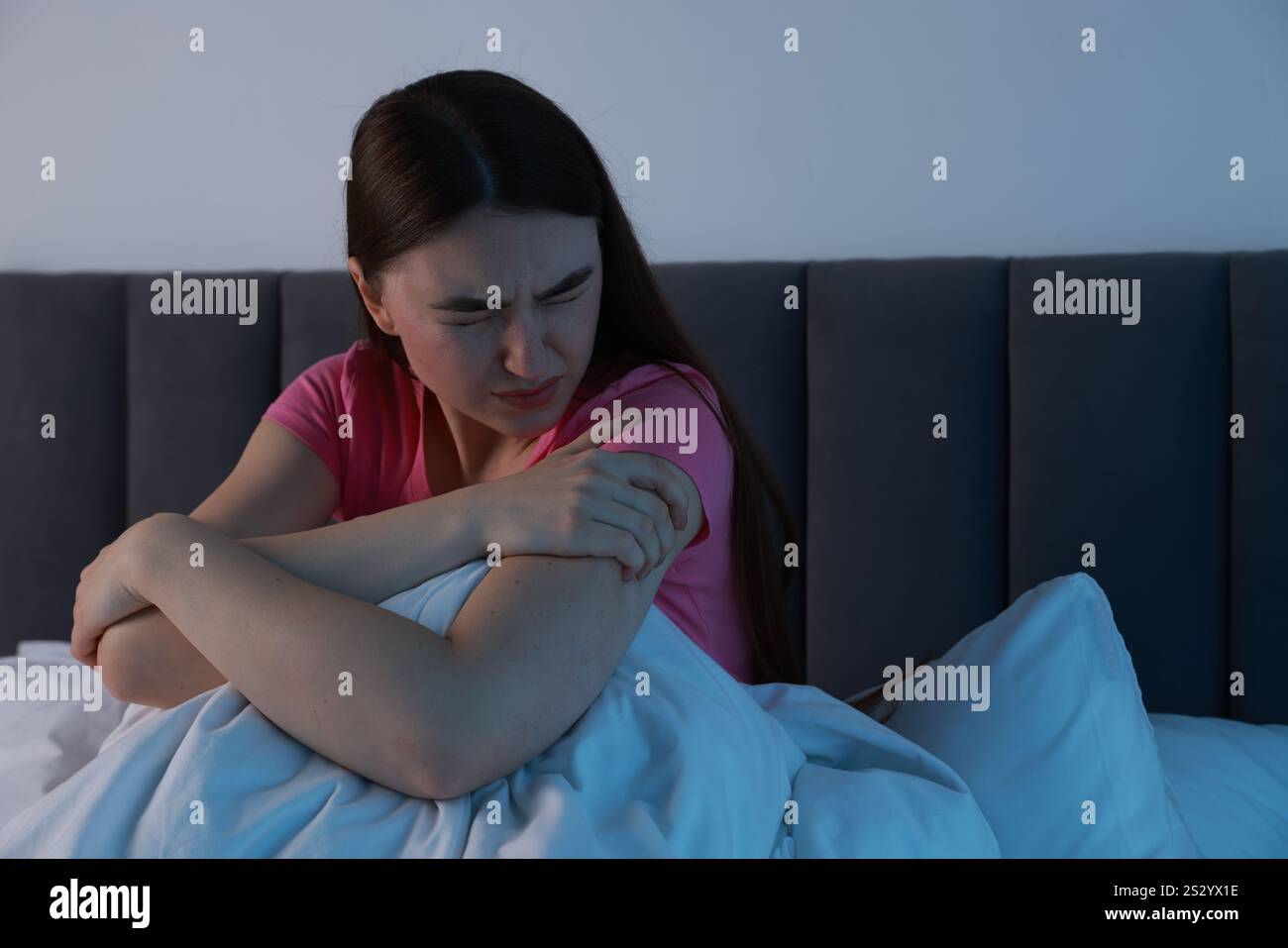 Fear of darkness. Scared young woman on bed in room at night Stock ...