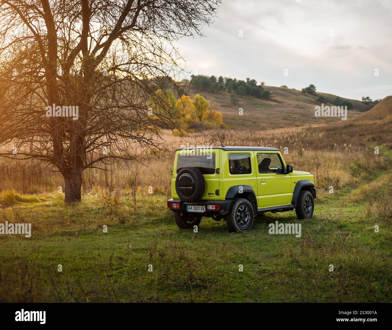 Lime green Suzuki Jimny in a valley. Rear three quarter view of off ...