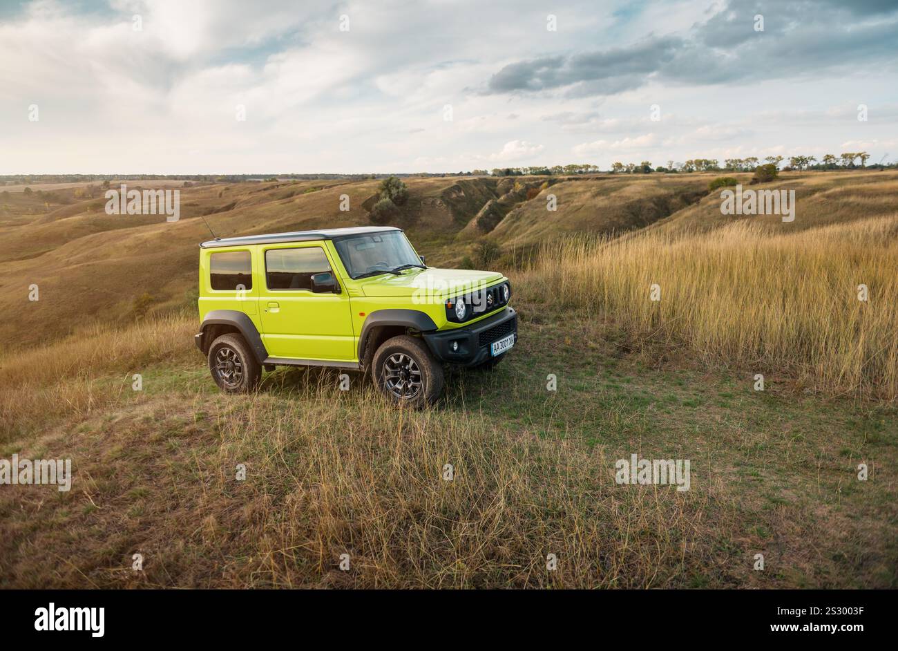Lime green Suzuki Jimny on top of the hill. Side view of off-road mini ...