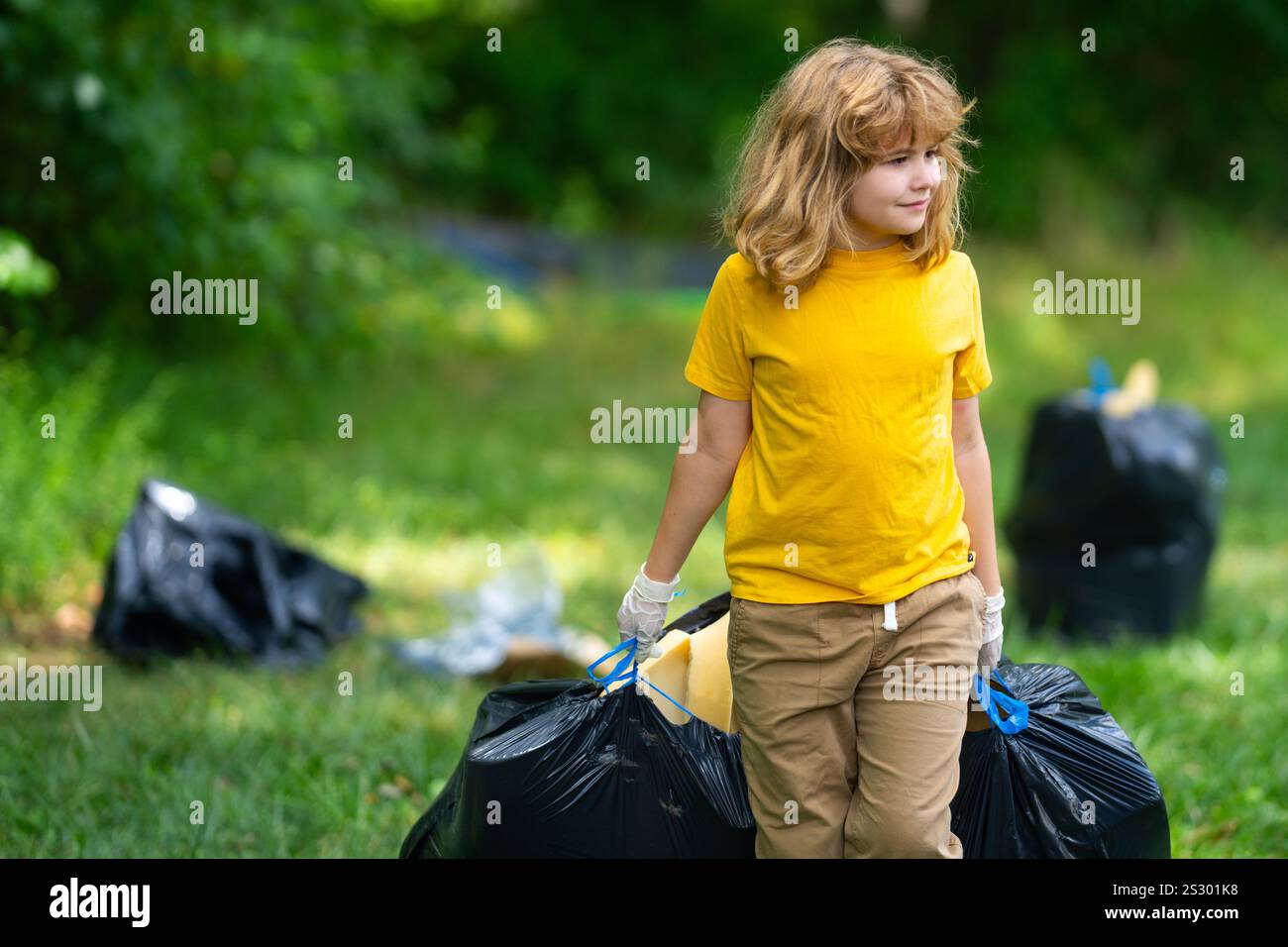 Environment plastic pollution. Volunteer kid collecting trash in the forest and holding a ...