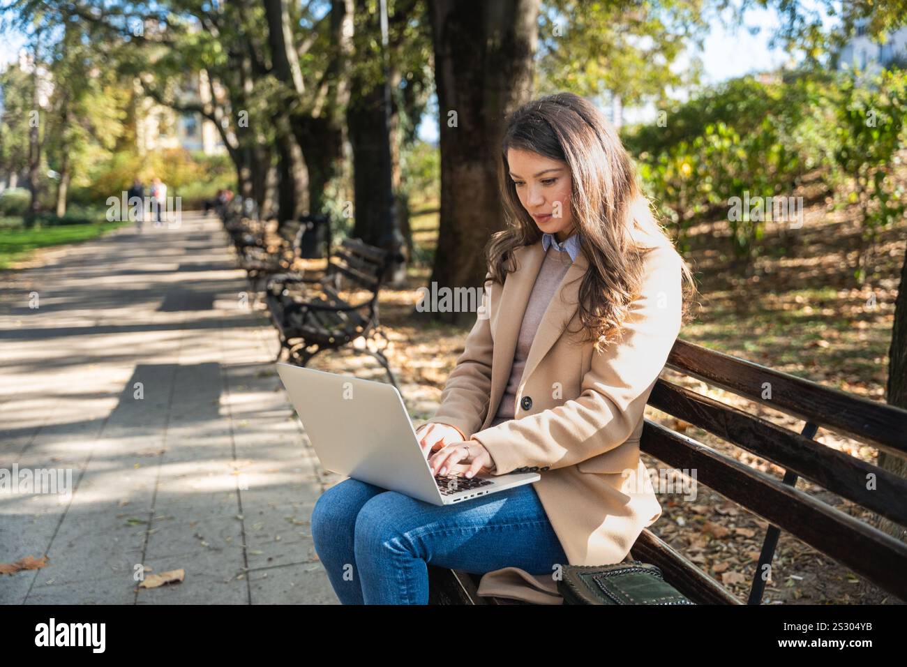 Elegant employer sitting on the bench. Business woman working on laptop ...