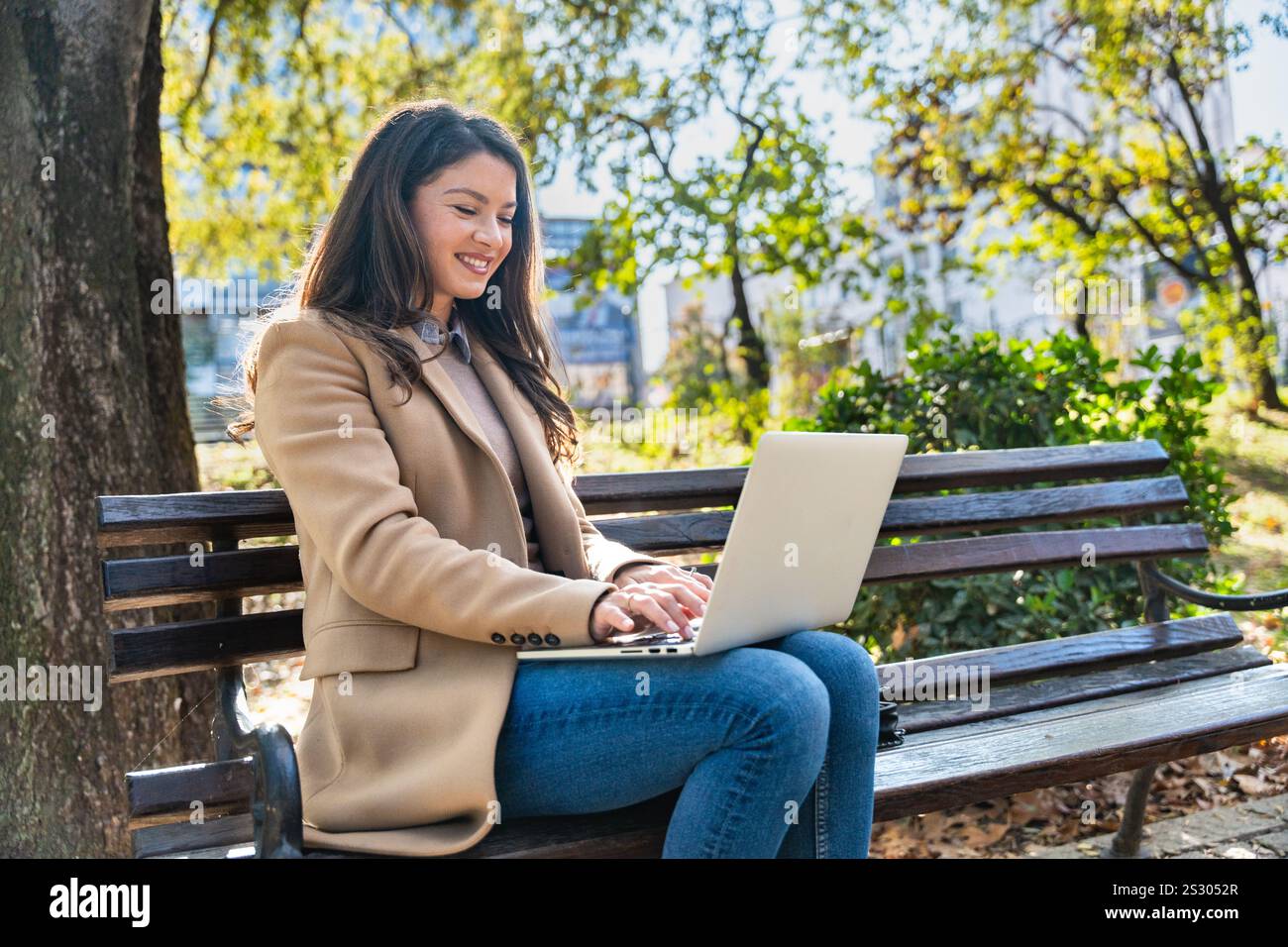 Elegant employer sitting on the bench. Business woman working on laptop ...