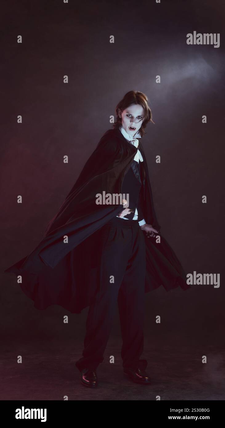 Man in black cape and suit. looks terrified, as vampire gazes forward ...