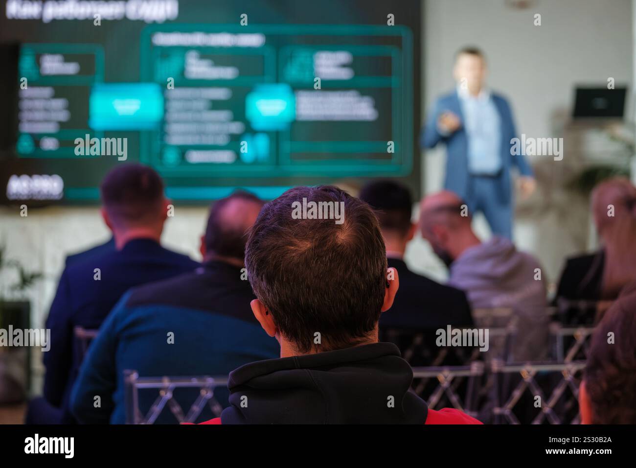 Professionals attending a presentation in a conference setting, with ...