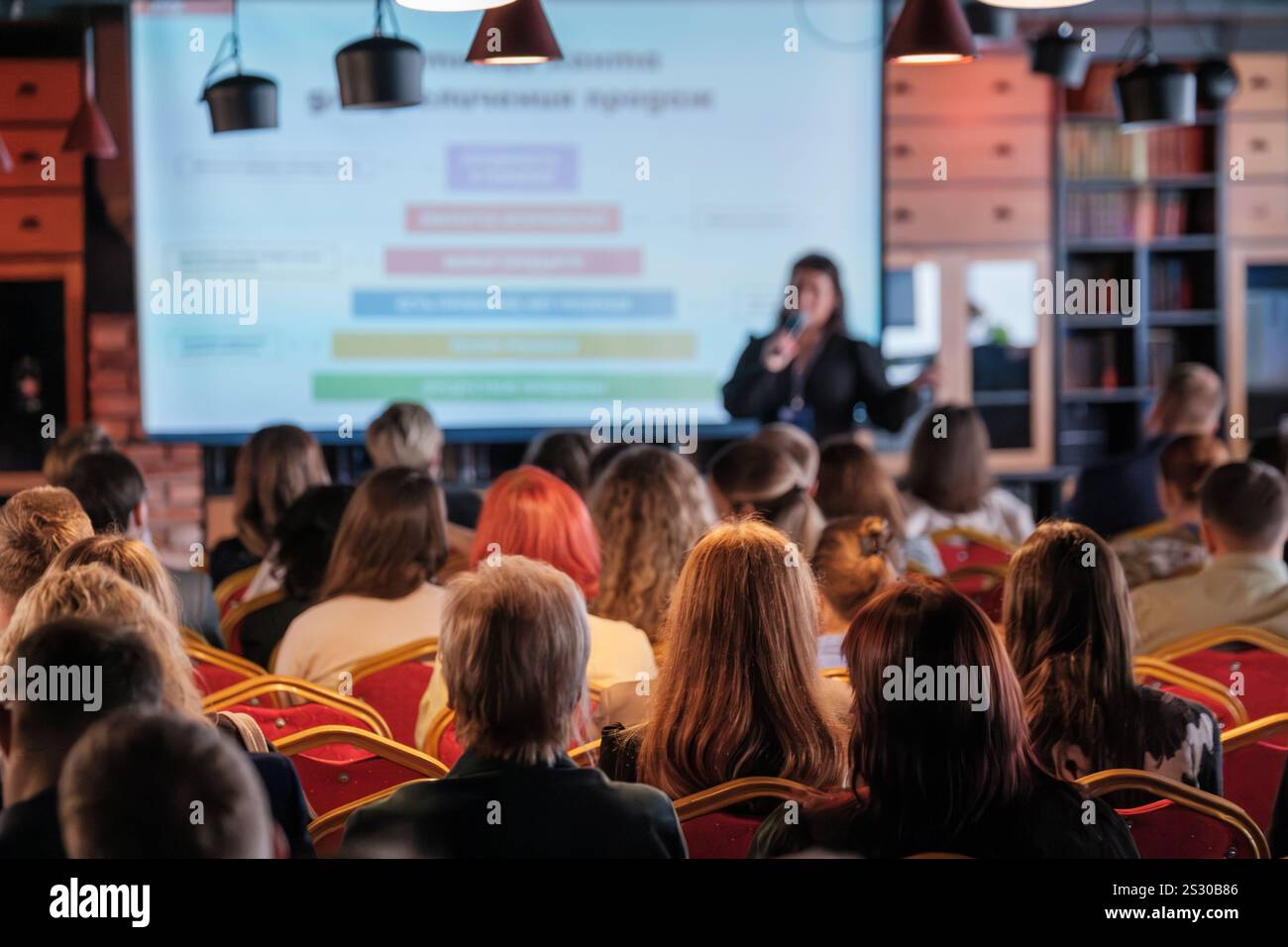 Conference attendees listen to a speaker in a modern venue with ...