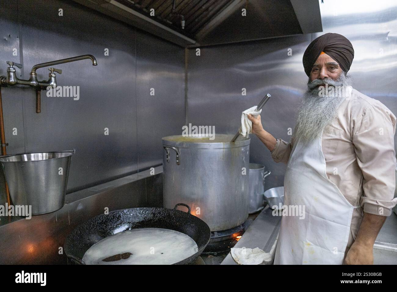 A volunteer Sikh cook prepares a vegetarian stew for any or all ...