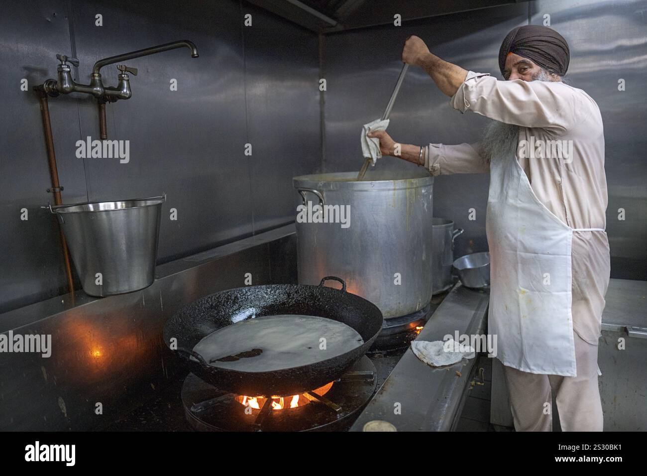 A volunteer Sikh cook prepares a vegetarian stew for any or all ...