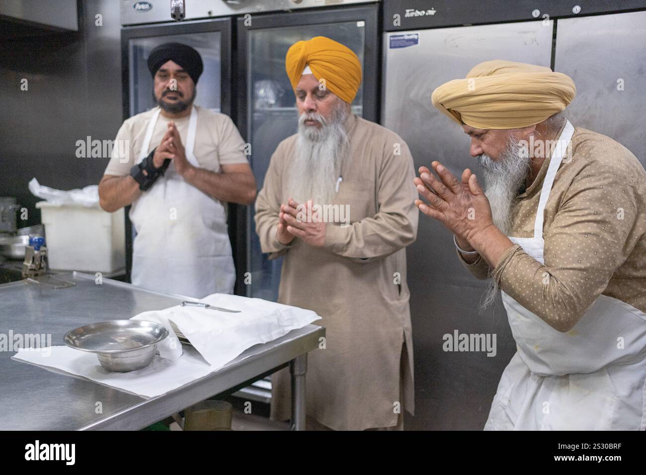 A priest (c) and kitchen workers bless food water & utensils in the ...