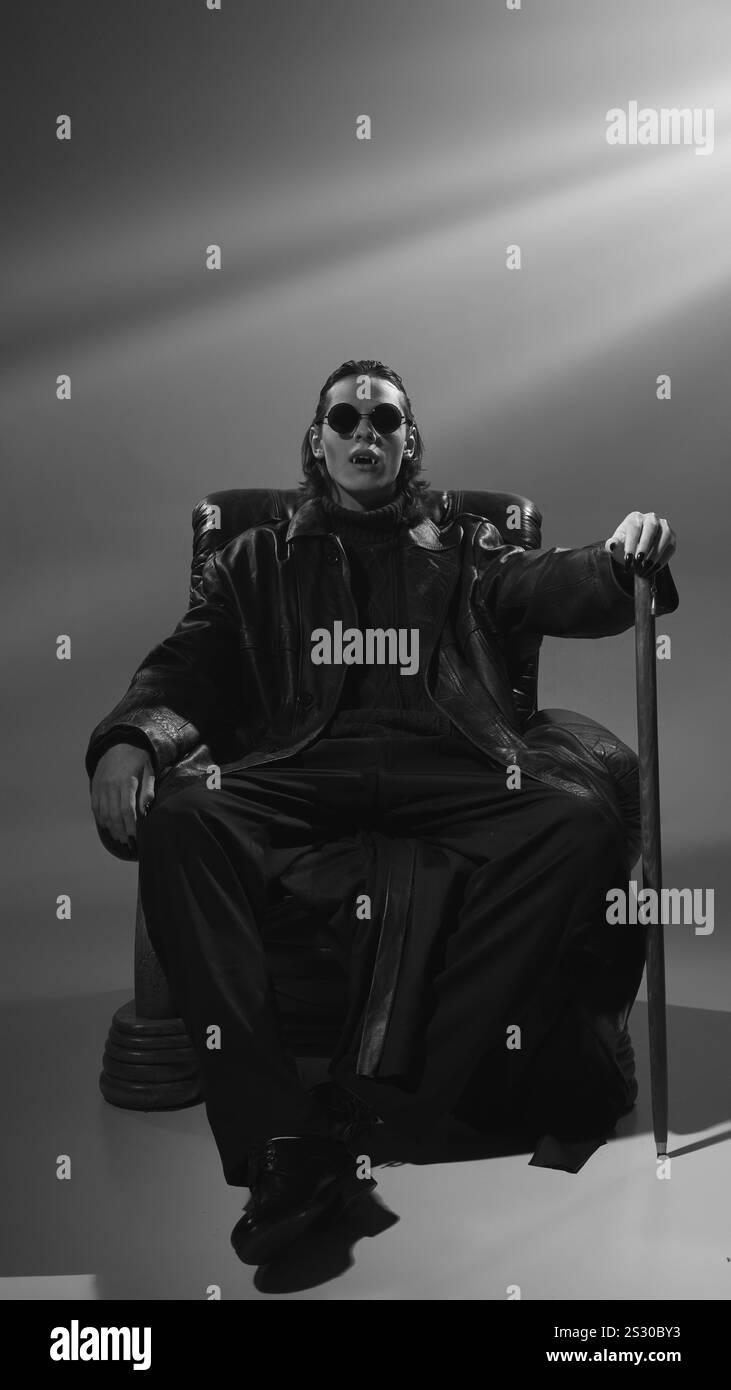 Black-and-white photo of man in leather coat and sunglasses sitting ...