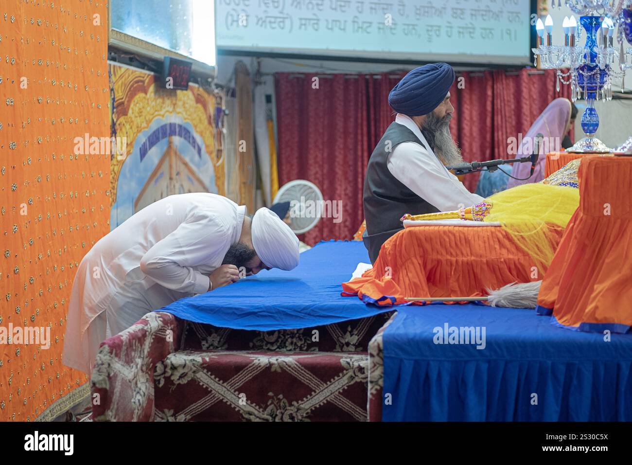 A priest bows down in respect behind the altar and holy book at the ...