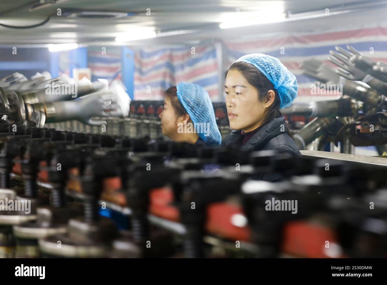 SUQIAN, CHINA - JANUARY 8, 2025 - A worker produces PVC gloves for export to Southeast Asia at ...
